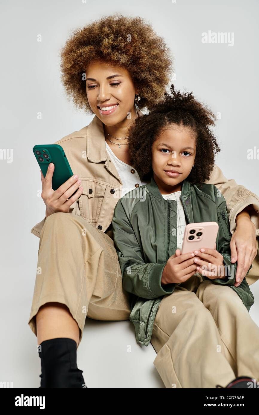 Curly African American mother and daughter sitting on floor, holding ...