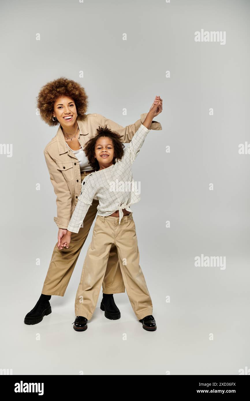 A curly African American mother and daughter in stylish clothes ...