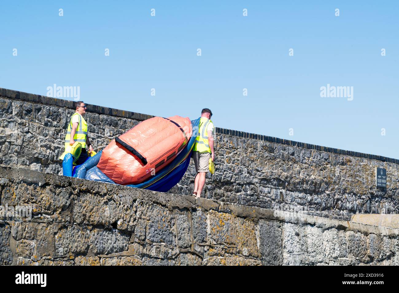 Two RNLI workers carrying an inflatable lifeboat at Rescue Fest 2024 ...