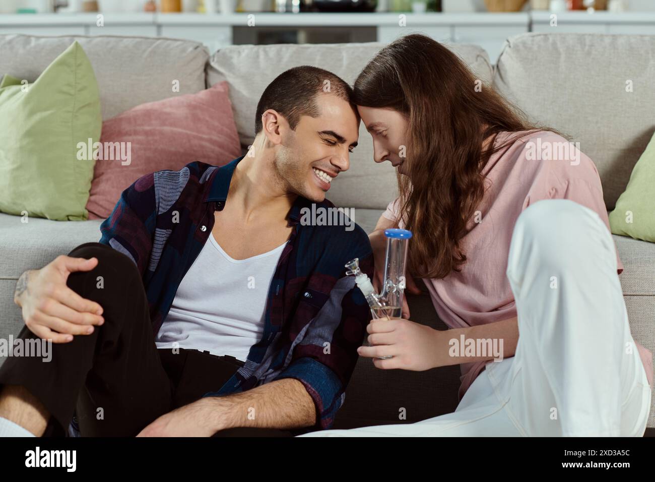 a gay couple, sit happily on a cozy couch in casual clothes, enjoying a ...