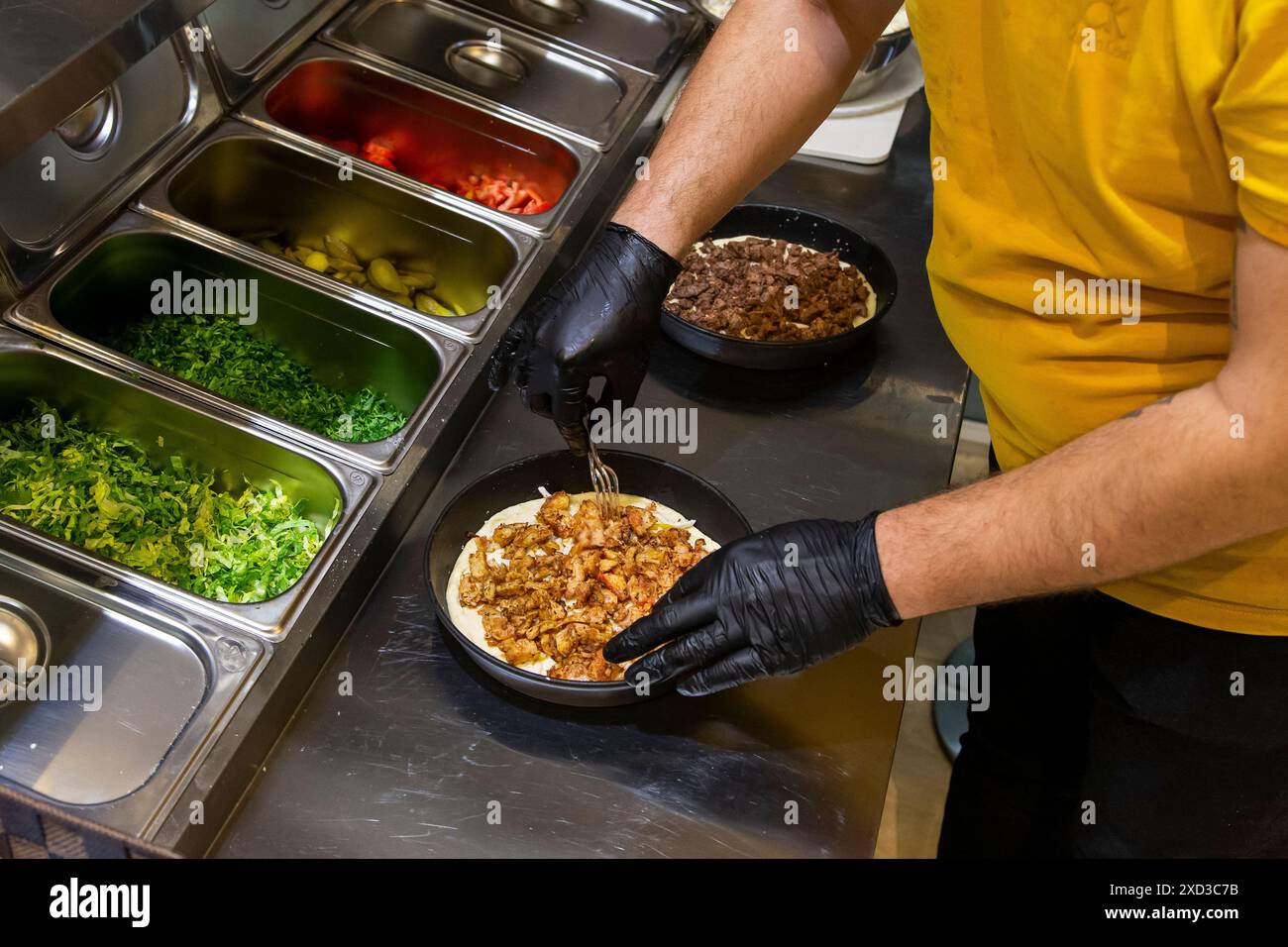 Chef putting fried chicken chips on a pizza in a restaurant kitchen ...