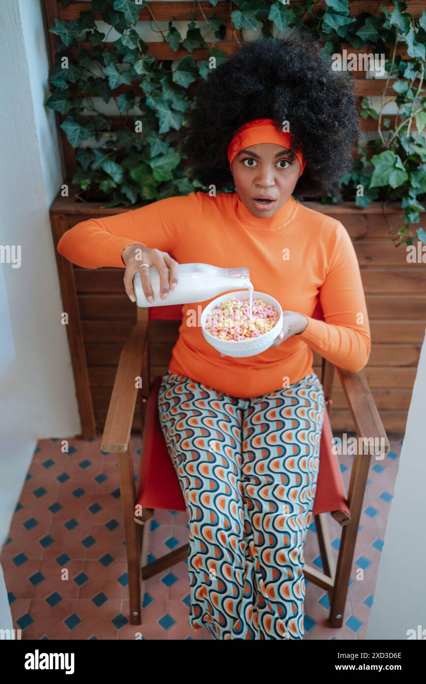 Woman in colorful retro outfit pours milk into a bowl of cereal with a ...