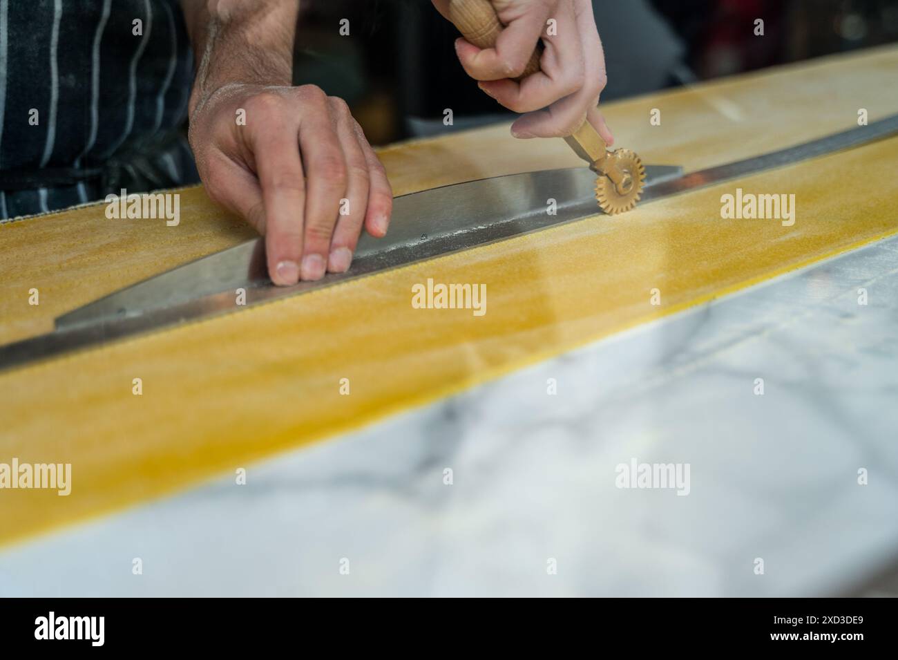 Close-up view of a cropped unrecognizable chef rolling out fresh pasta ...