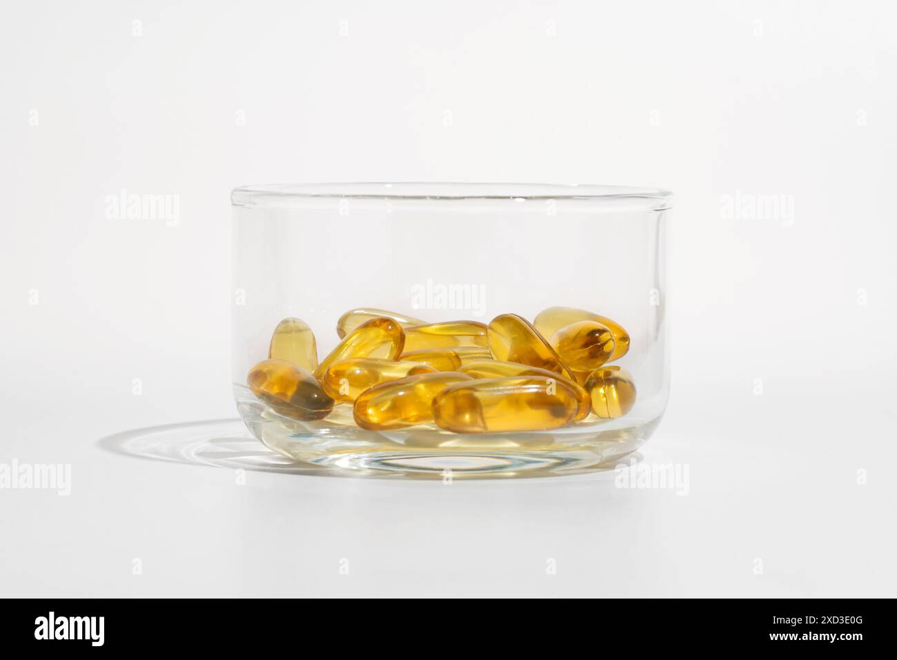 A clear glass dish filled with golden, translucent Omega 3 capsules ...