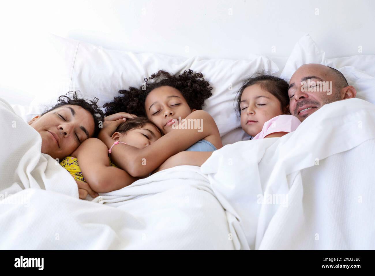 A serene scene of a multiethnic family sleeping together, captured with ...
