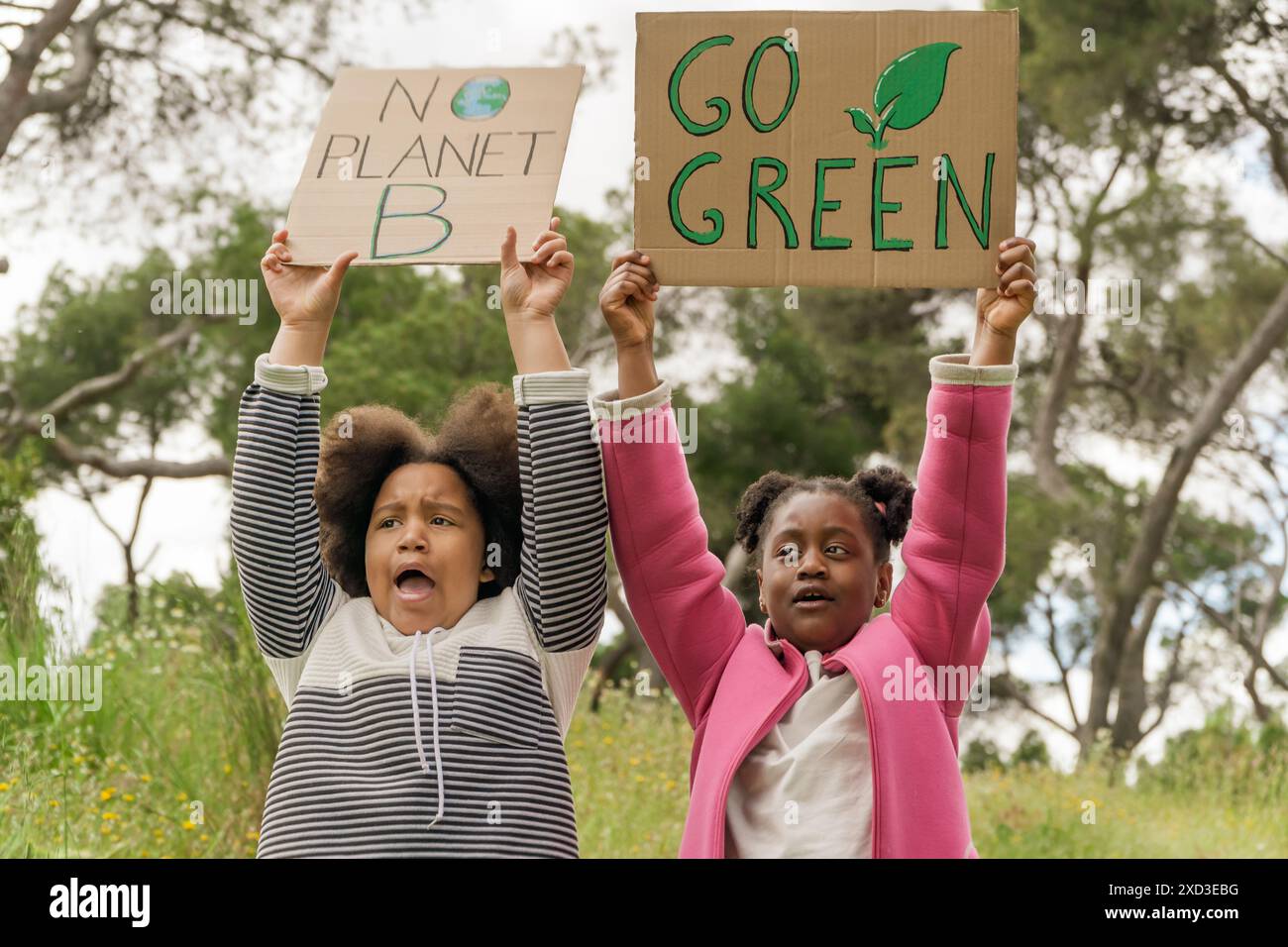 Two young African-American girls hold up hand-made environmental ...