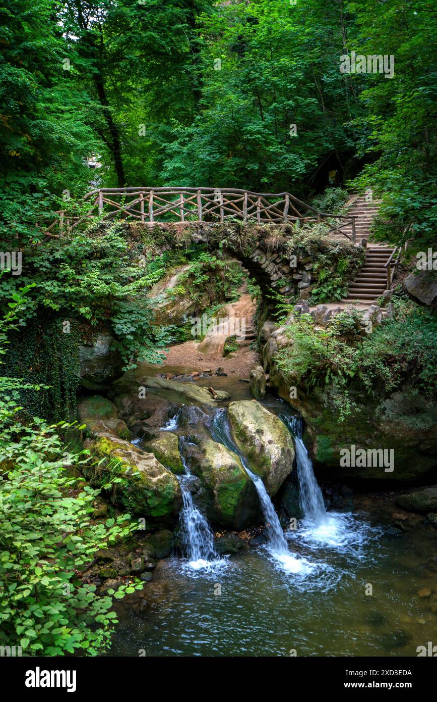 A charming old stone bridge spans the cascading waters of ...