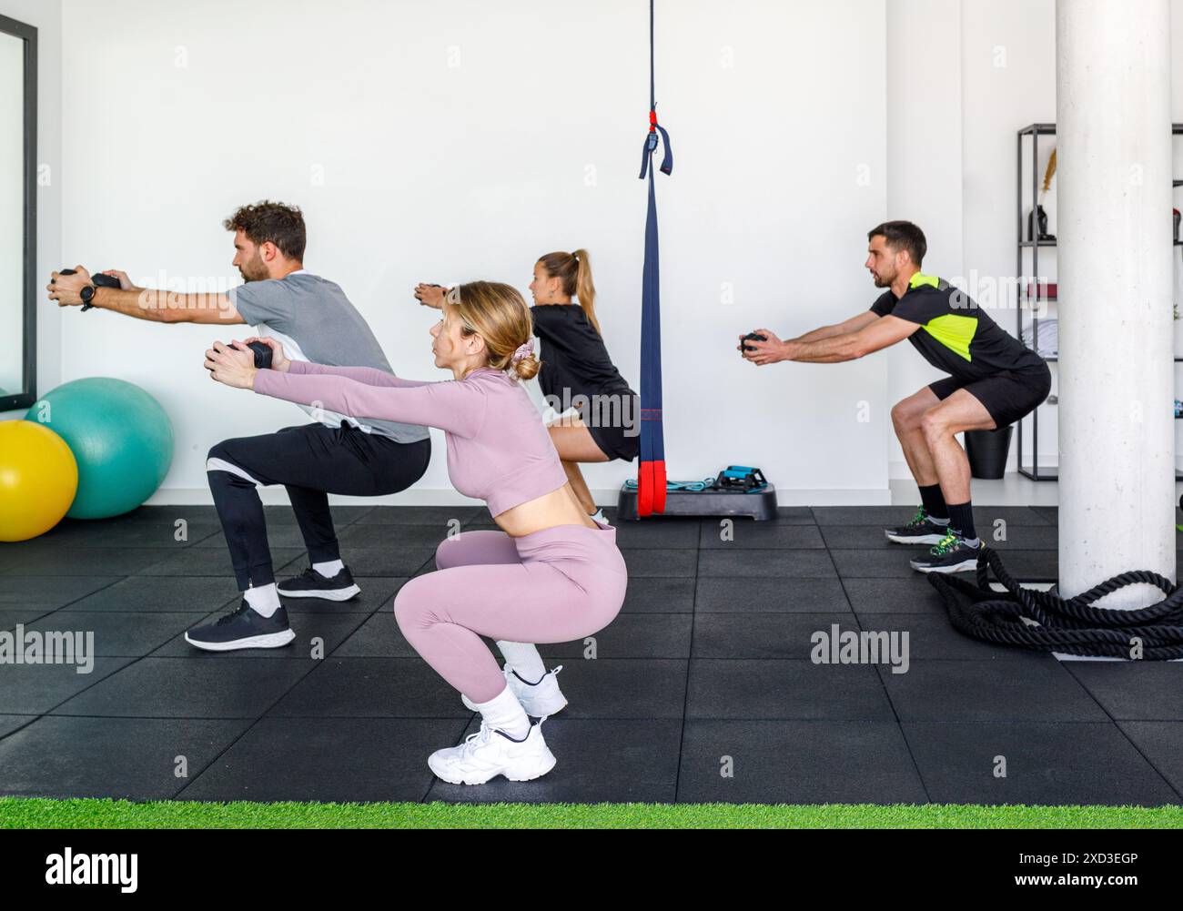 Four individuals engage in a squatting exercise together in a well ...
