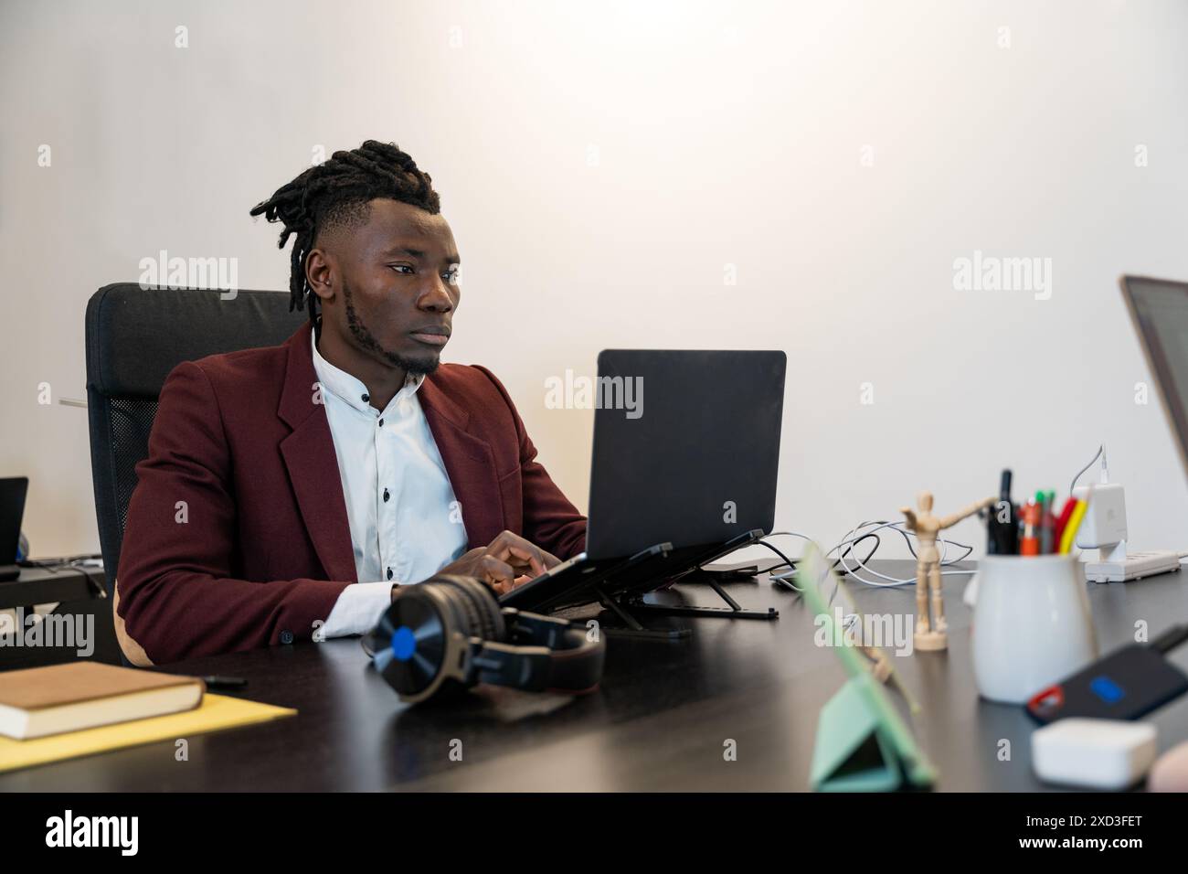 A focused professional man, dressed in a maroon blazer and white shirt ...