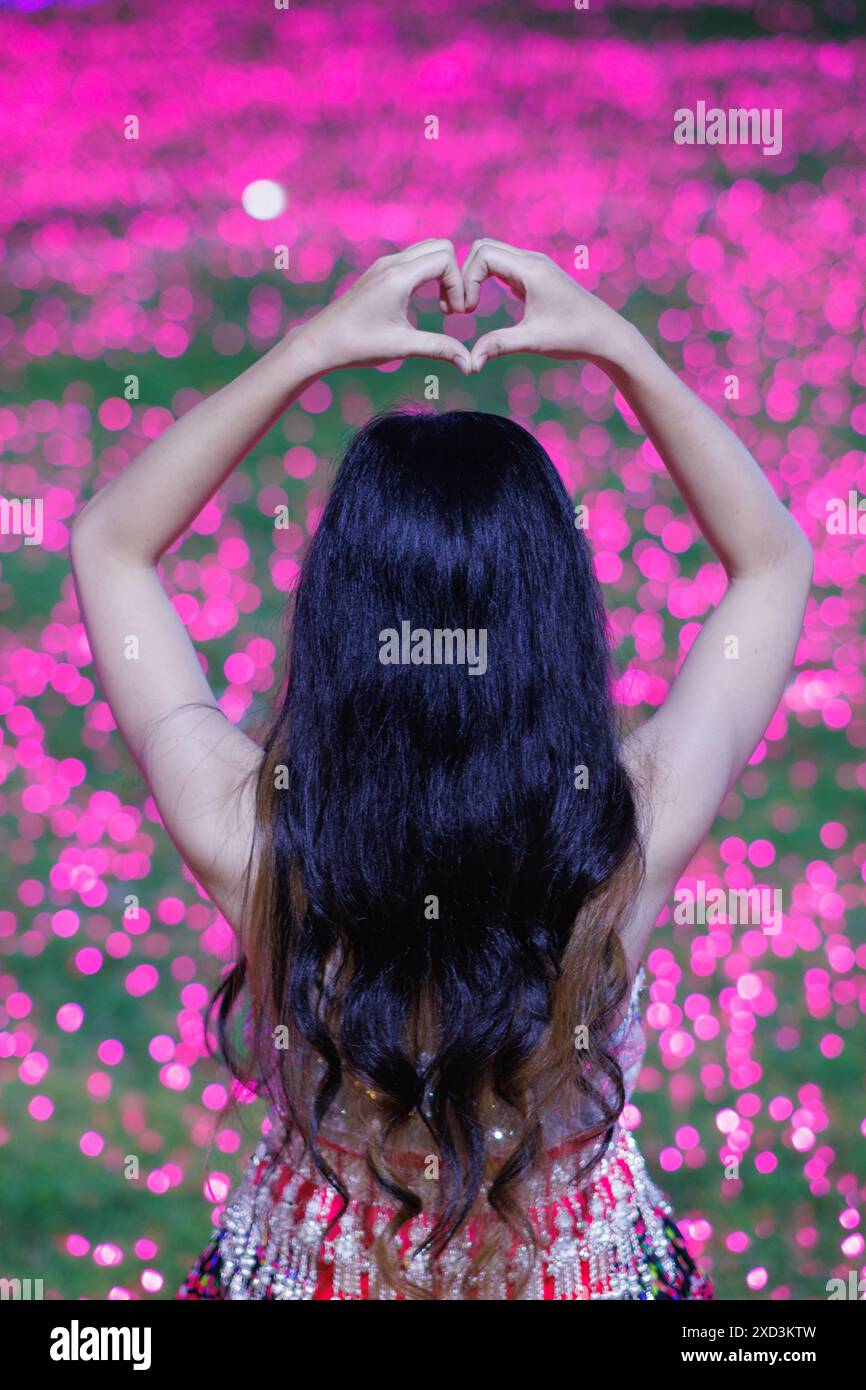 woman raises her hands to make heart symbol that represents love and ...