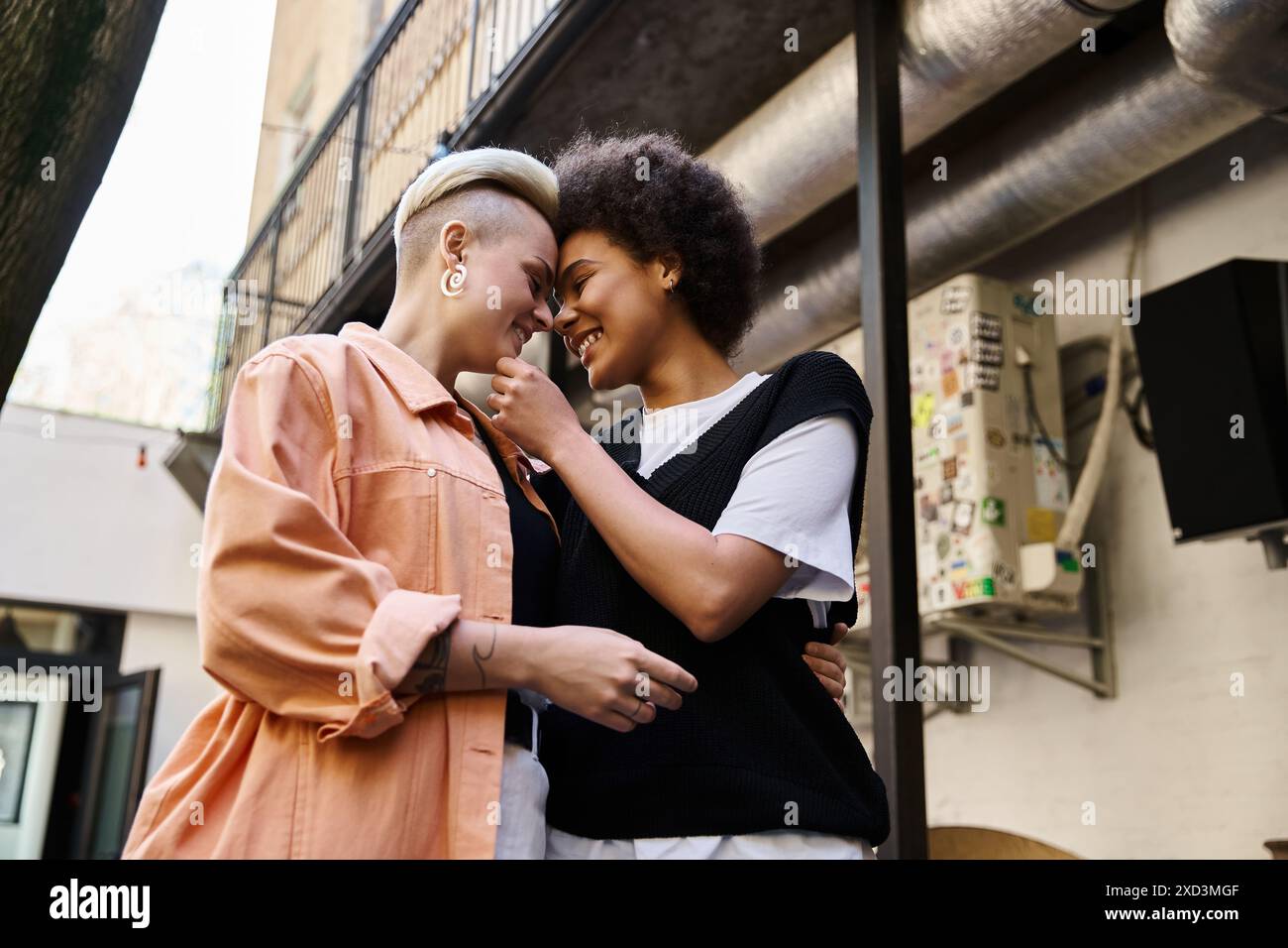 Two diverse women standing in a loving embrace in a cafe Stock Photo ...