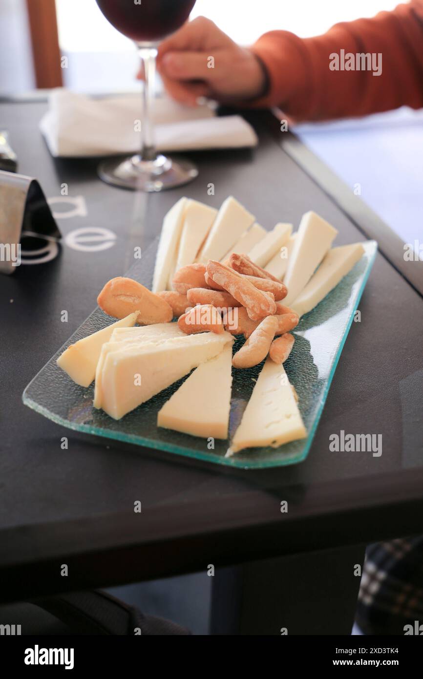 Tapa of sliced Manchego cheese and red wine in a Spanish bar in ...