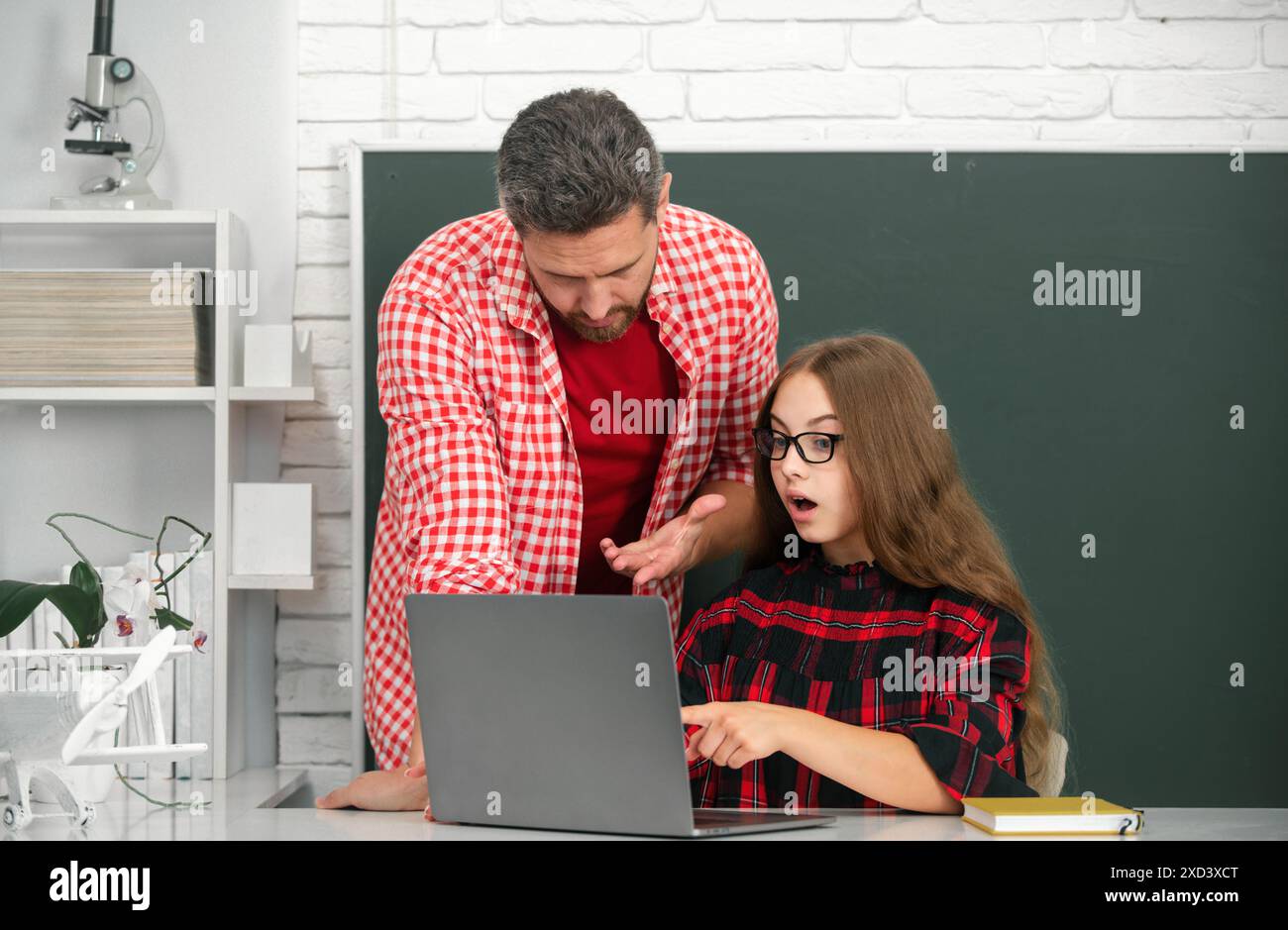 Teacher helping elementary school pupils in computer class, learning with laptop. Elementary ...