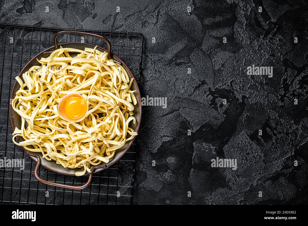 Dry spaetzle egg noodle in a steel tray. Black background. Top view ...