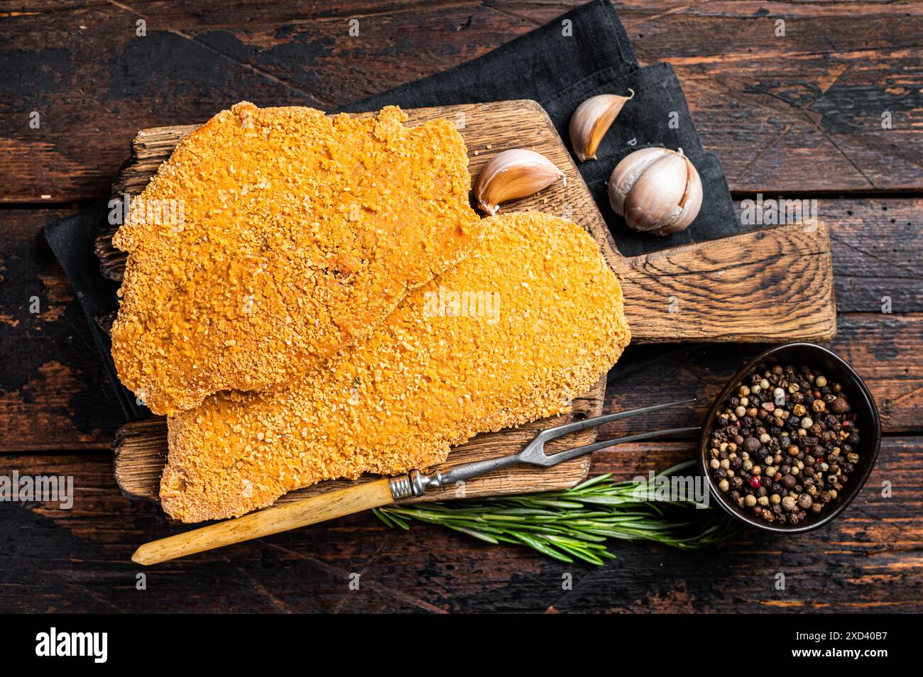 Uncooked Wiener schnitzel in breadcrumbs, raw pork meat. Wooden ...