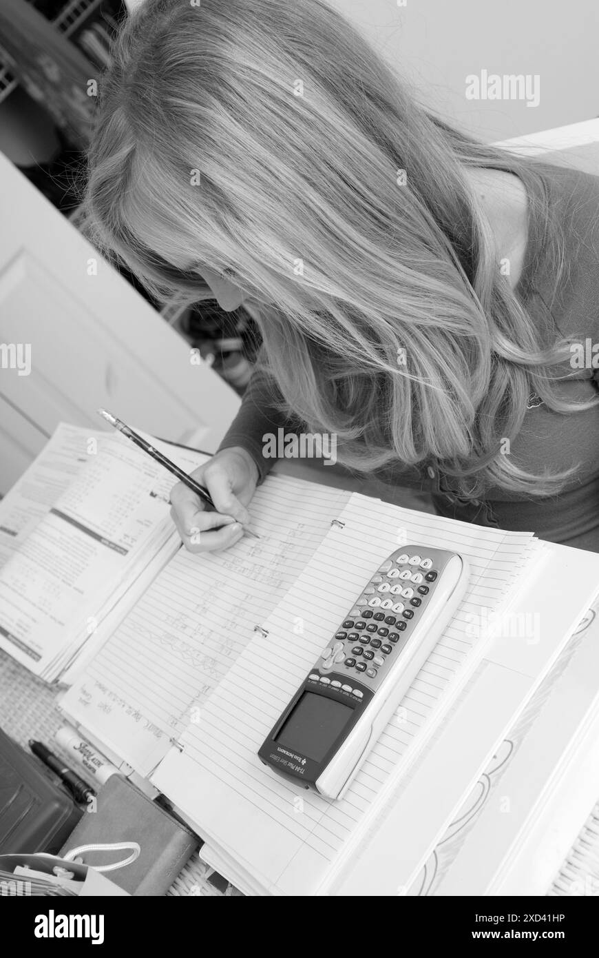 Focused Caucasian teenage girl diligently working on her math homework ...