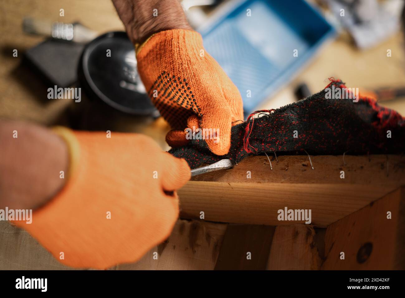 elderly man's hands in orange gloves removing old upholstery from chair ...