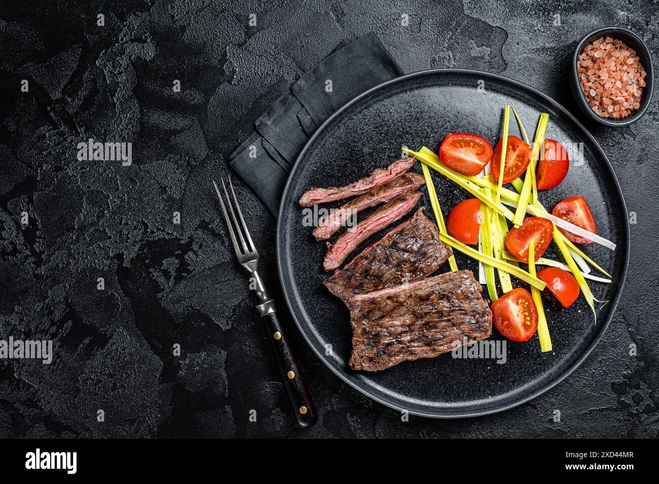 Grilled arrachera Skirt steak with garnish. Black background. Top view ...