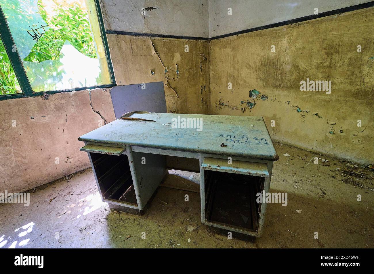 An abandoned room with an old desk, crumbling walls and damaged windows ...