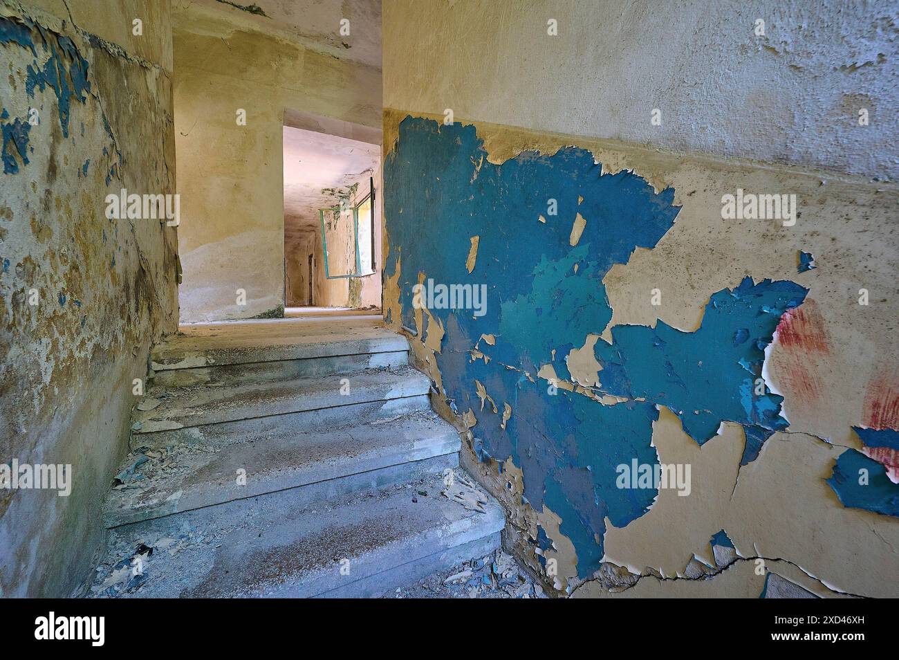 Dilapidated staircase with blue and yellow peeling paint in a ruined ...