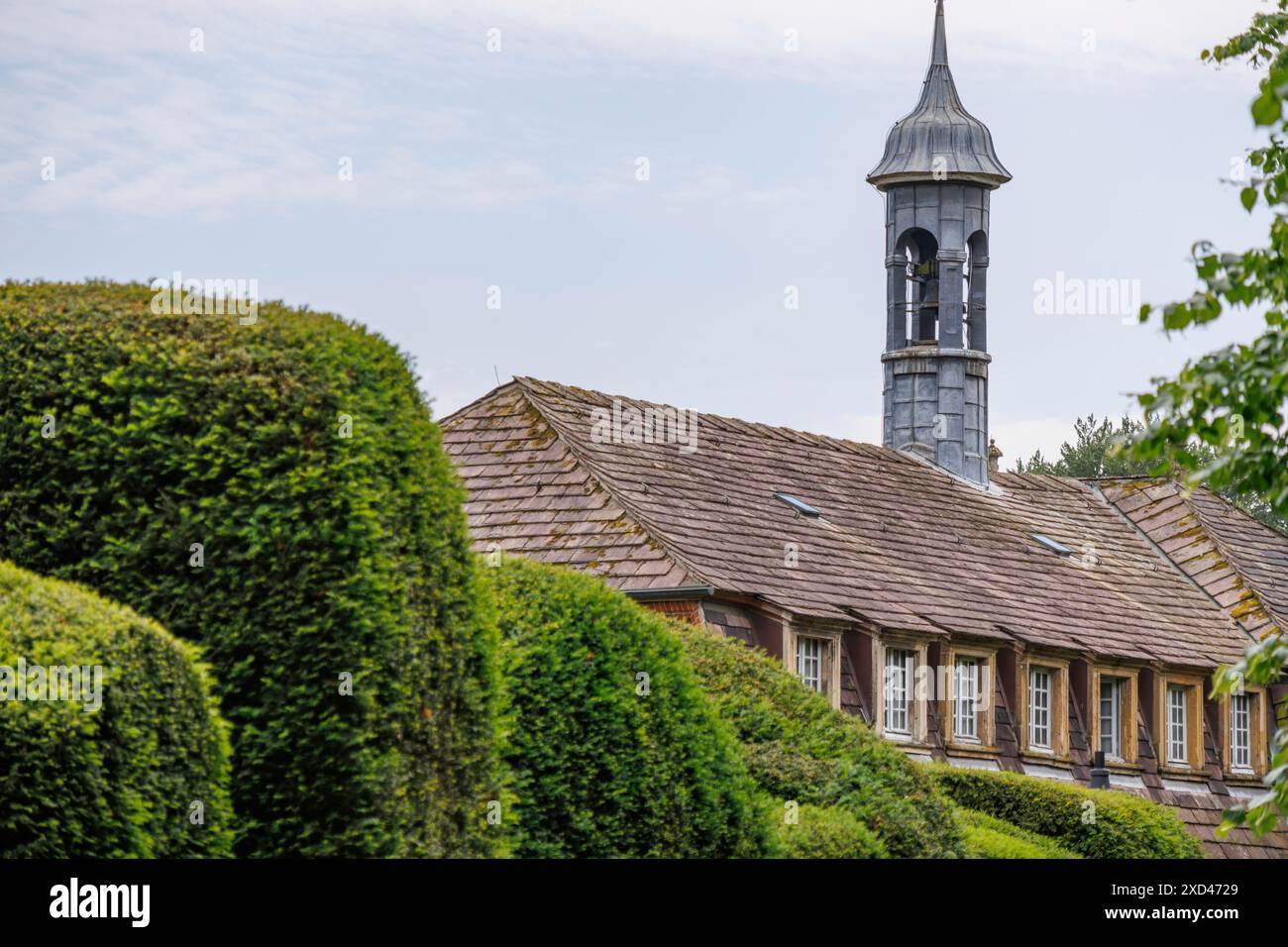 Building with a striking tower and shingle-covered roof, surrounded by ...