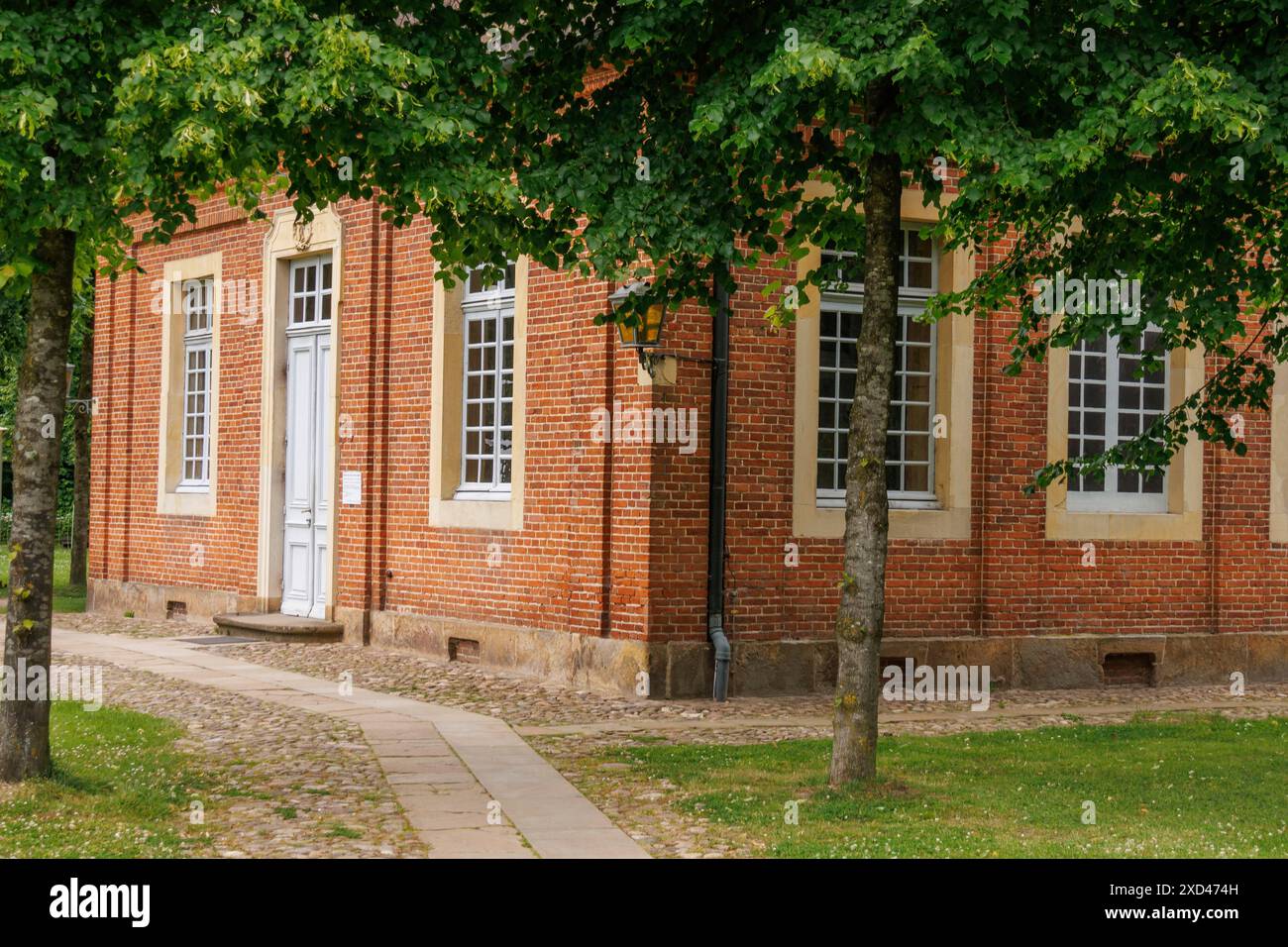 Historic brick building with white windows and doors, flanked by tall ...