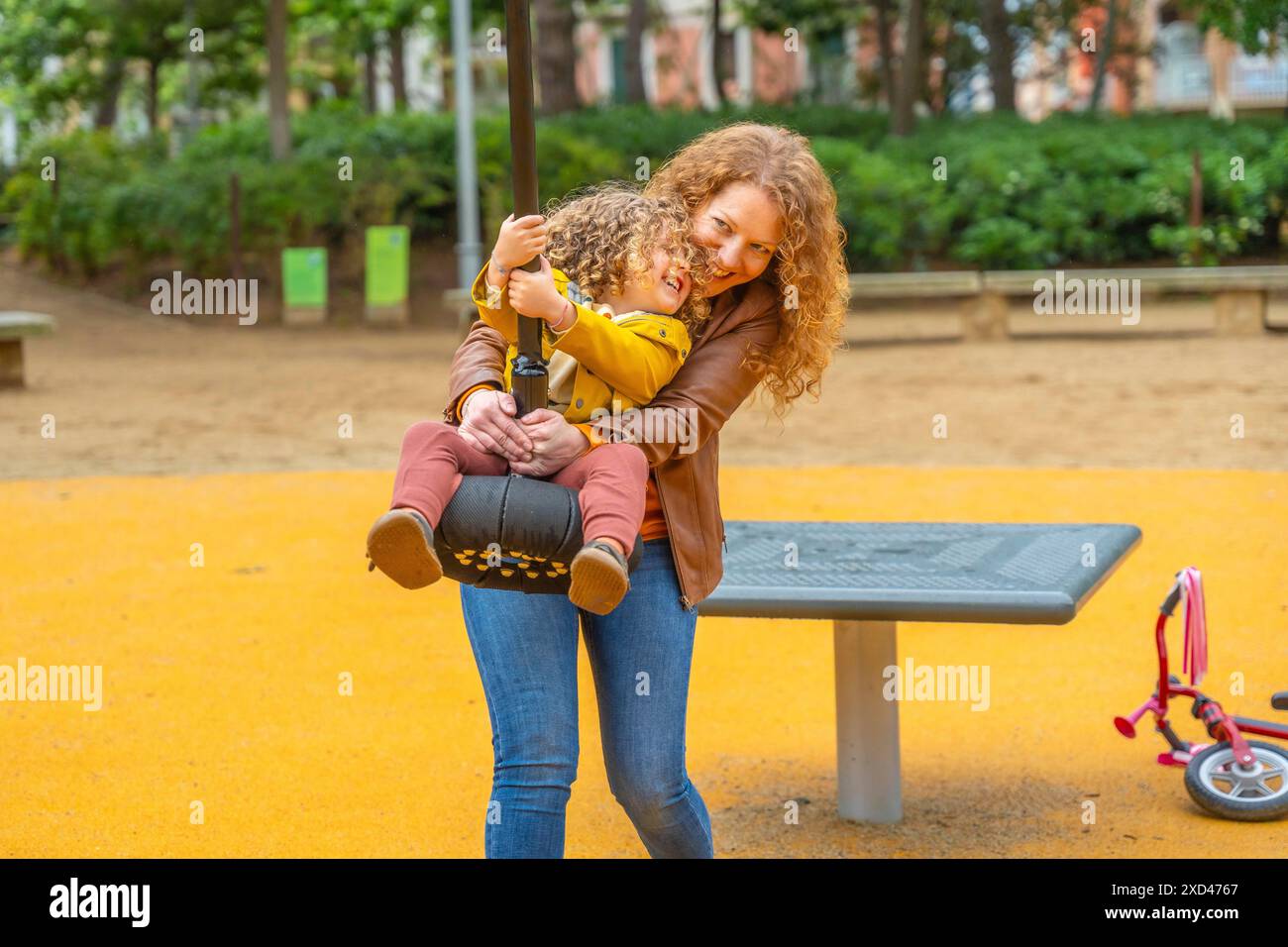 Caucasian adult mother ready to push a girl on swing in a park Stock ...