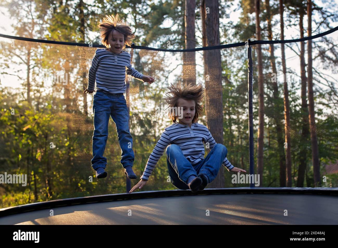 Sweet preteen boy jumping on trampoline making somersaults in the air ...
