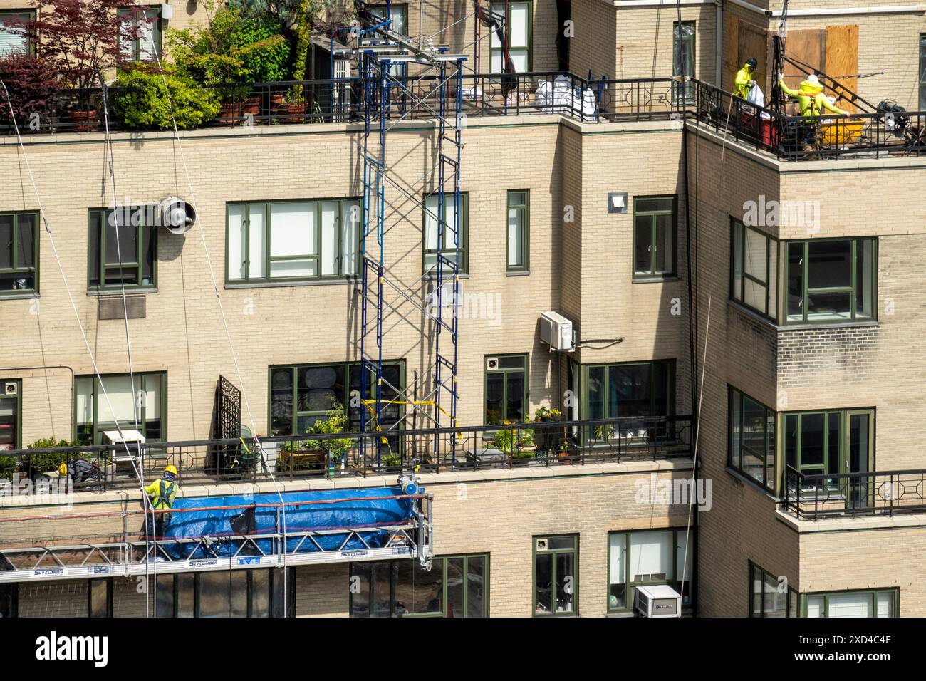 Construction workers on an Apartment Building in New York City in a suspended basket, Midtown ...