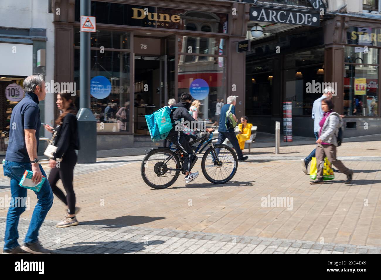 Food delivery cyclist riding an e-bike through the centre of Leeds on a ...