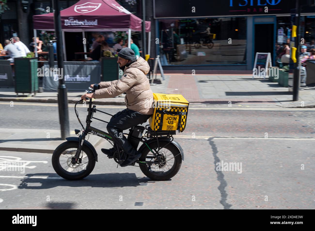 Food delivery cyclist riding an e-bike through the centre of Leeds on a ...