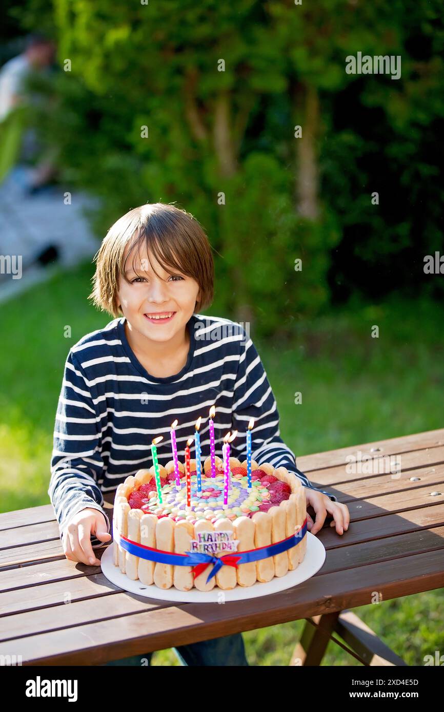 Sweet preteen boy, celebrating his birhtday with colorful cake outdoors ...