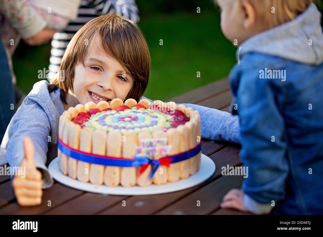 Sweet preteen boy, celebrating his birhtday with colorful cake outdoors ...