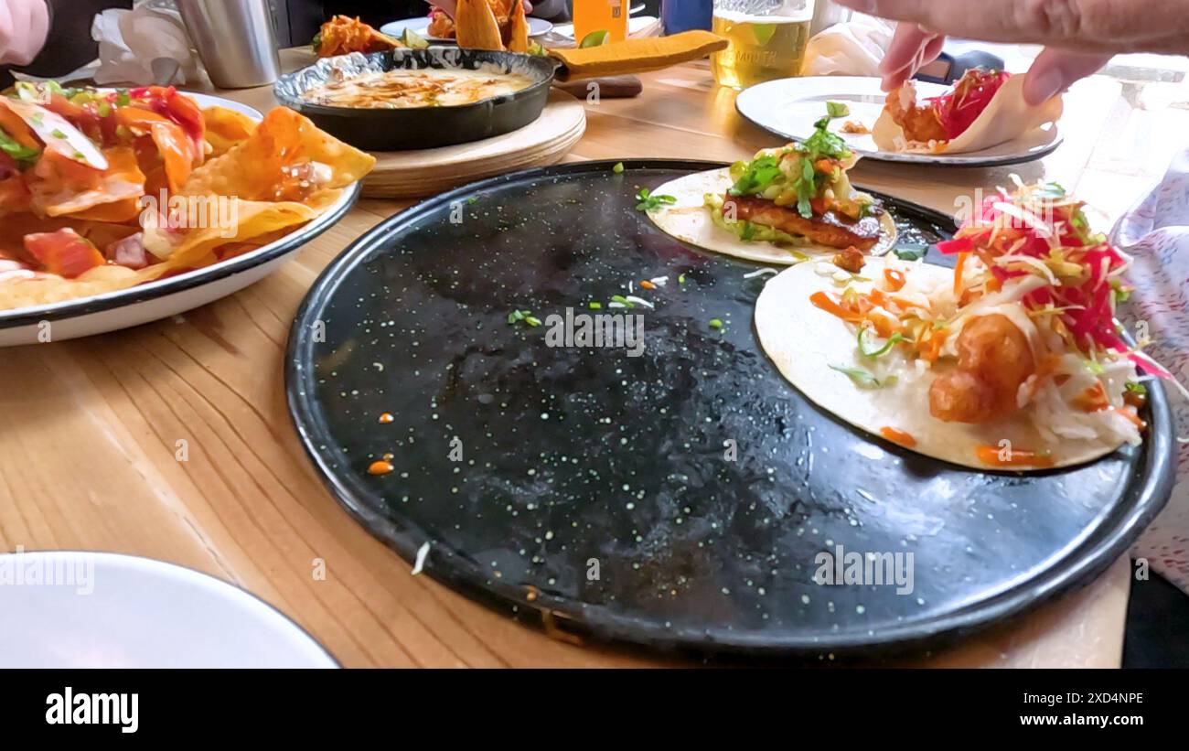Hand Picking Up Tacos at a Restaurant Table Stock Photo - Alamy