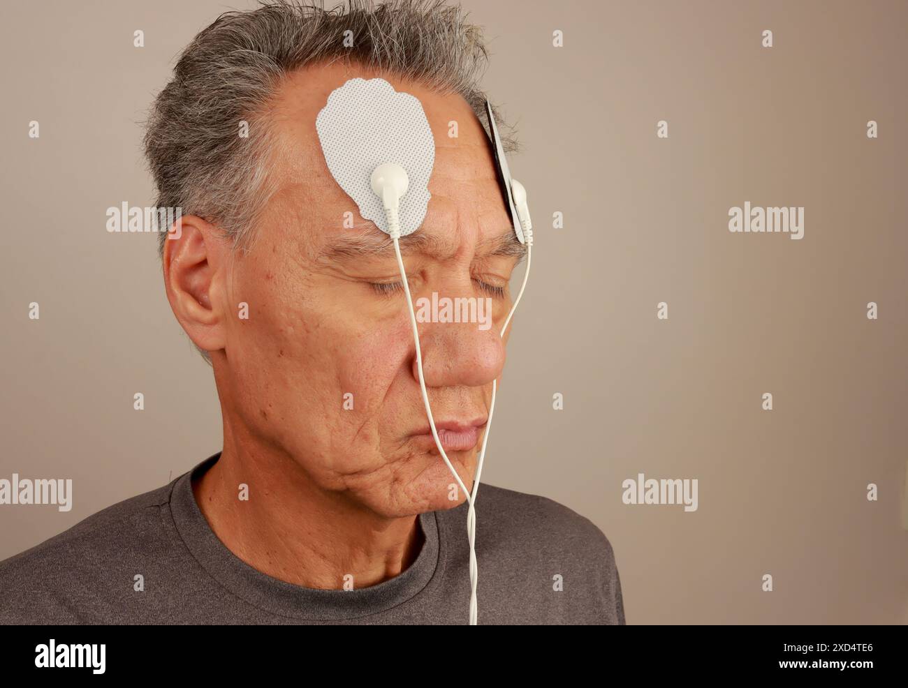 Elderly man undergoing a medical procedure with electrodes attached to ...