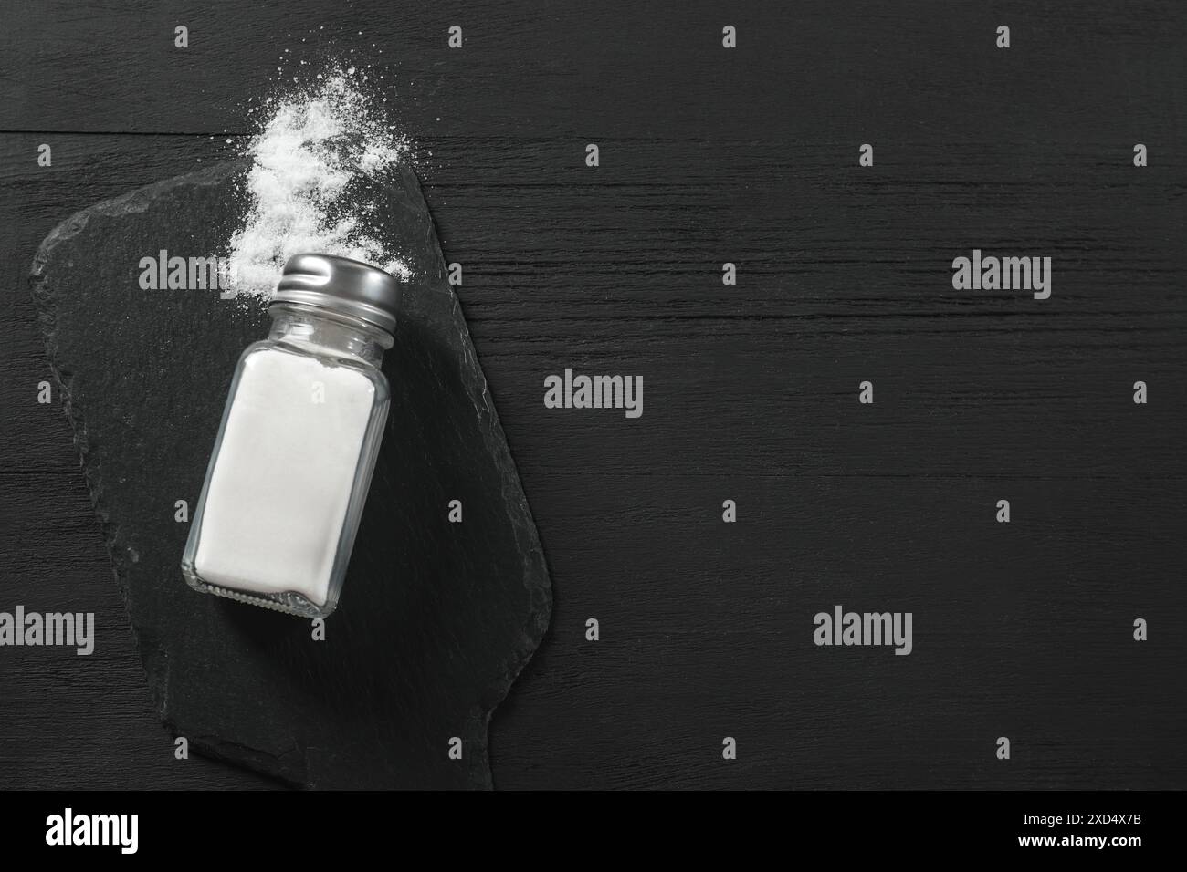 Salt shaker on black wooden table, top view. Space for text Stock Photo ...