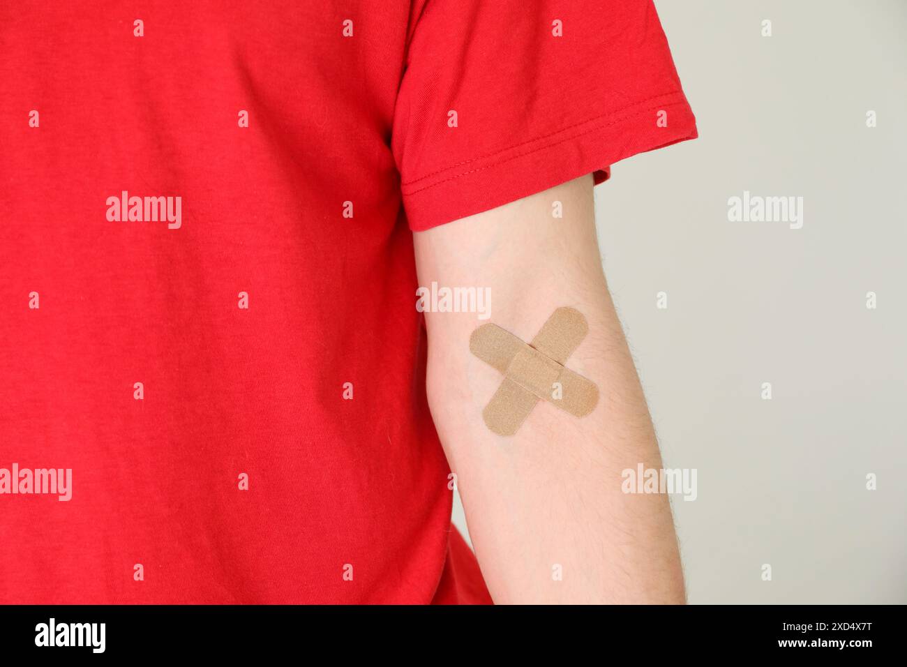 Blood donation. Woman with sticking plaster on her arm against gray ...