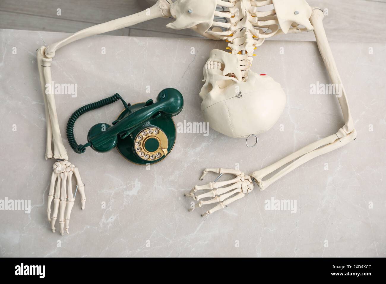 Waiting concept. Human skeleton at grey marble table with corded ...