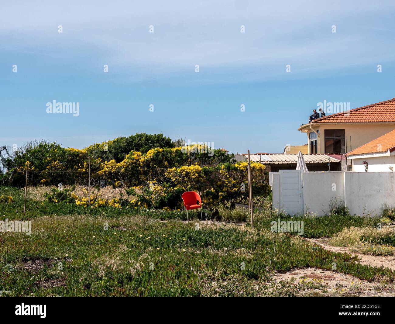 old red plastic chair standing in the green field.two man sitting on ...