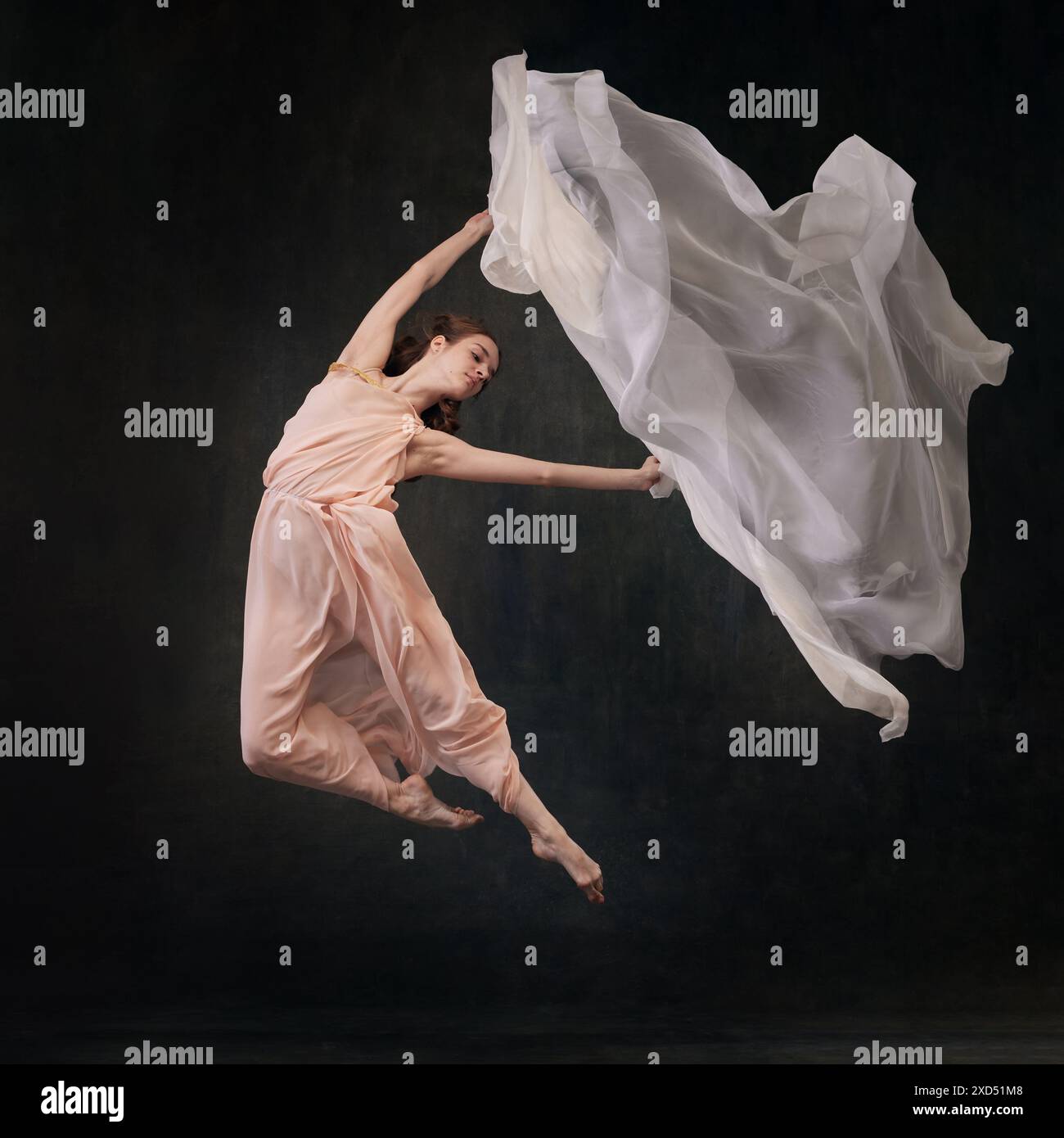 Beautiful ballerina dancer in mid-jump, her movements accentuated by ...