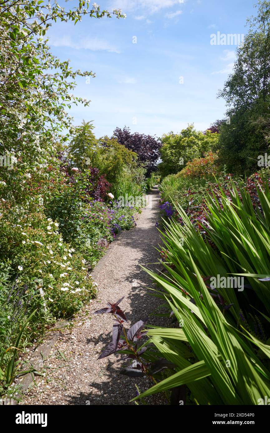 Scenic view of a serene English garden pathway lined with lush greenery ...