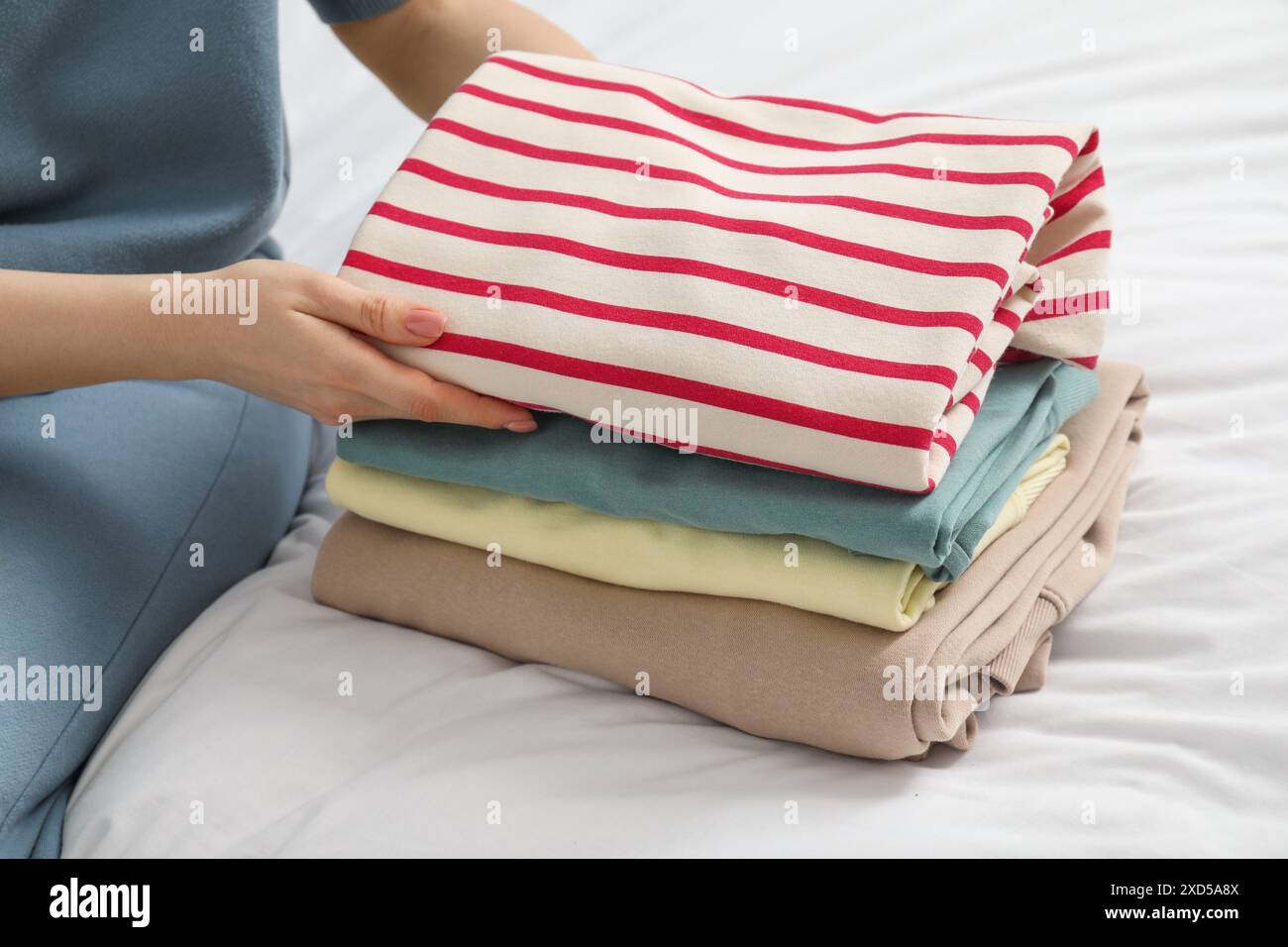 Woman folding clean clothes on bed, closeup Stock Photo - Alamy