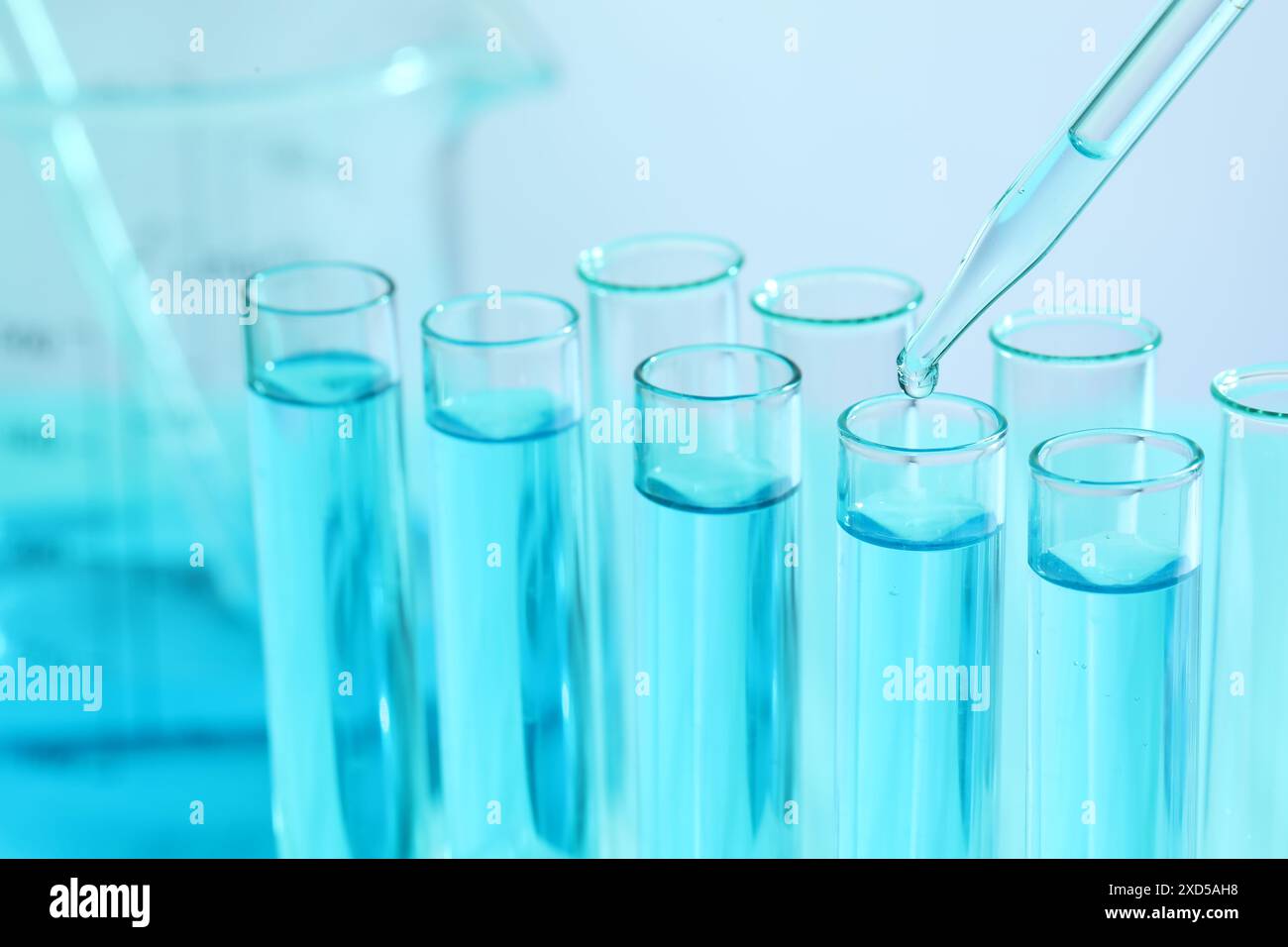 Dripping liquid from pipette into test tube on blurred background ...