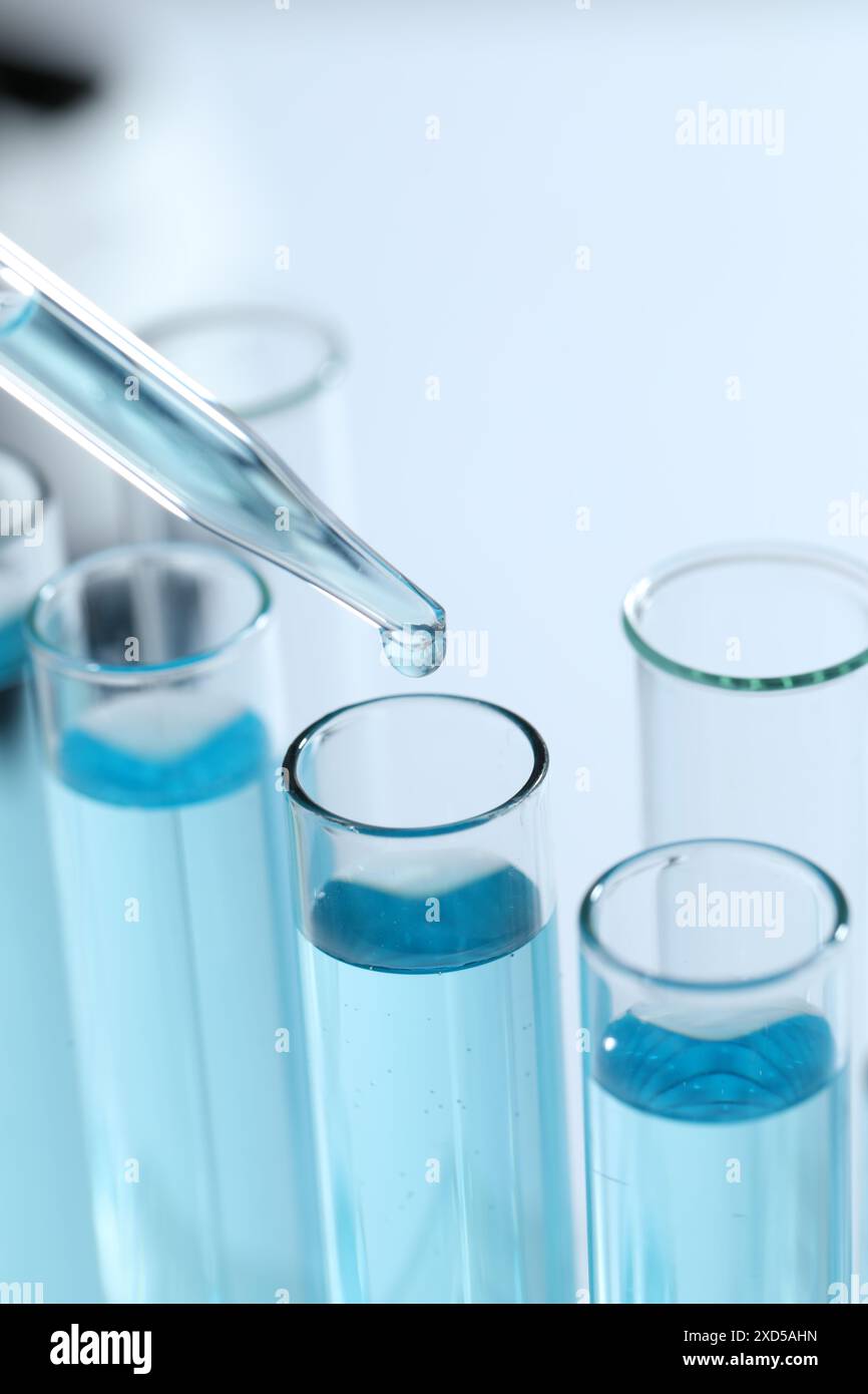 Dripping liquid from pipette into test tube on blurred background ...