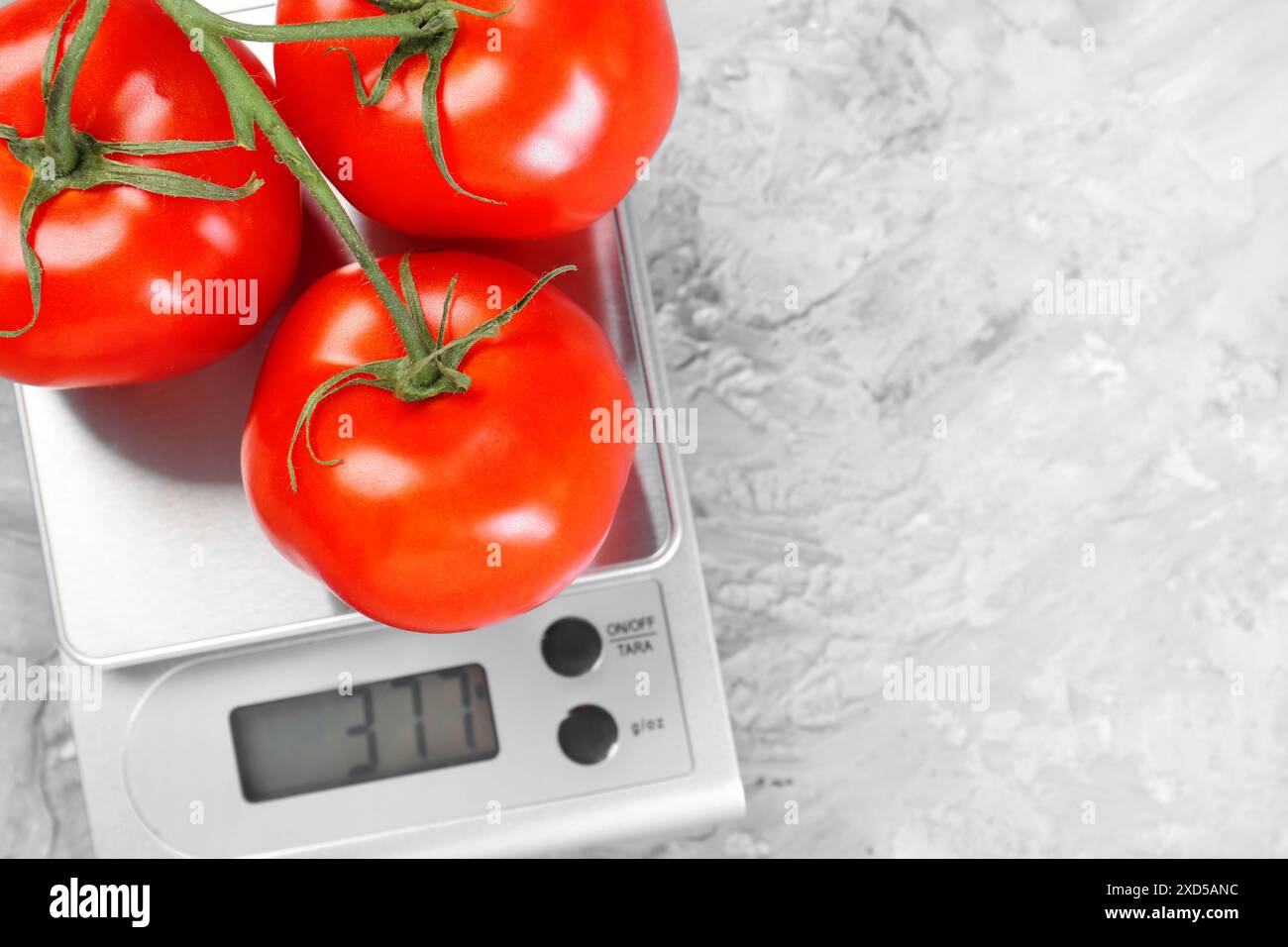 Kitchen scale with tomatoes on grey textured table, top view. Space for ...