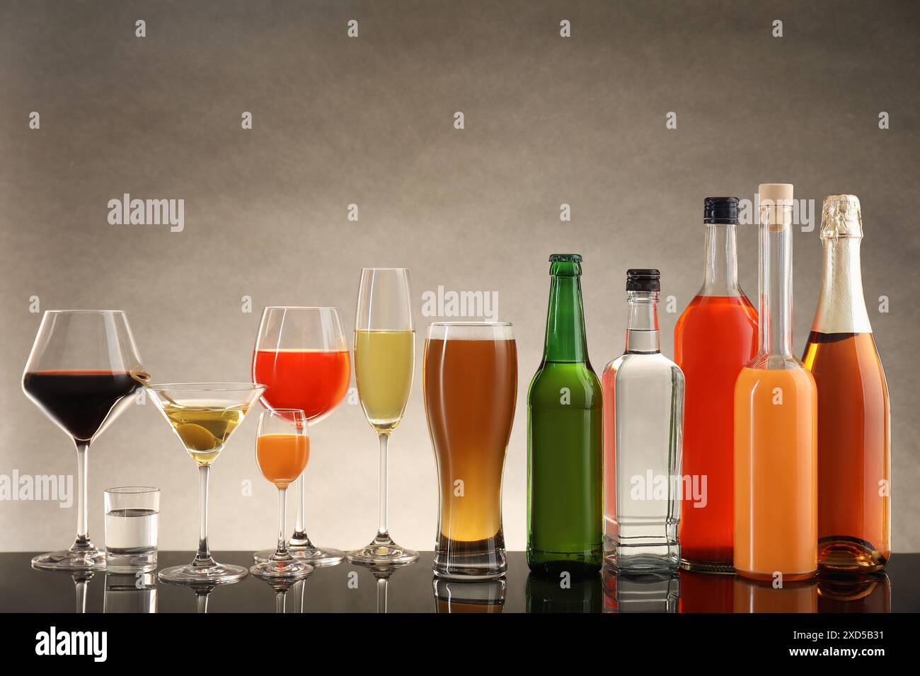 Bottles and glasses with different alcoholic drinks on table against ...