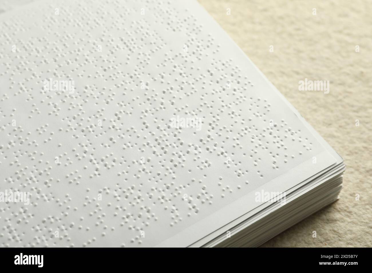 Book with Braille text on beige textured table, closeup. Education and ...