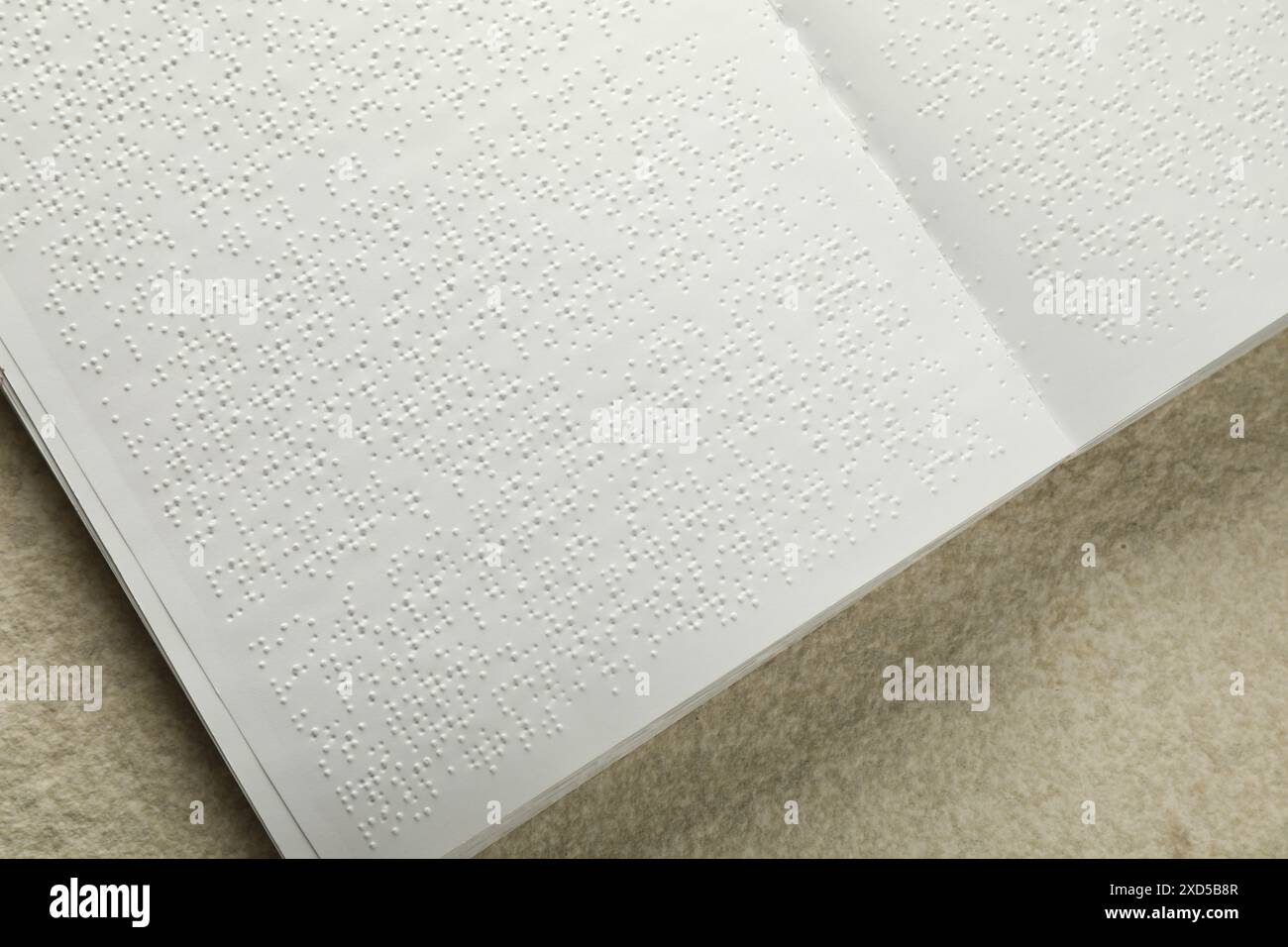 Book with Braille text on beige textured table, top view. Education and ...