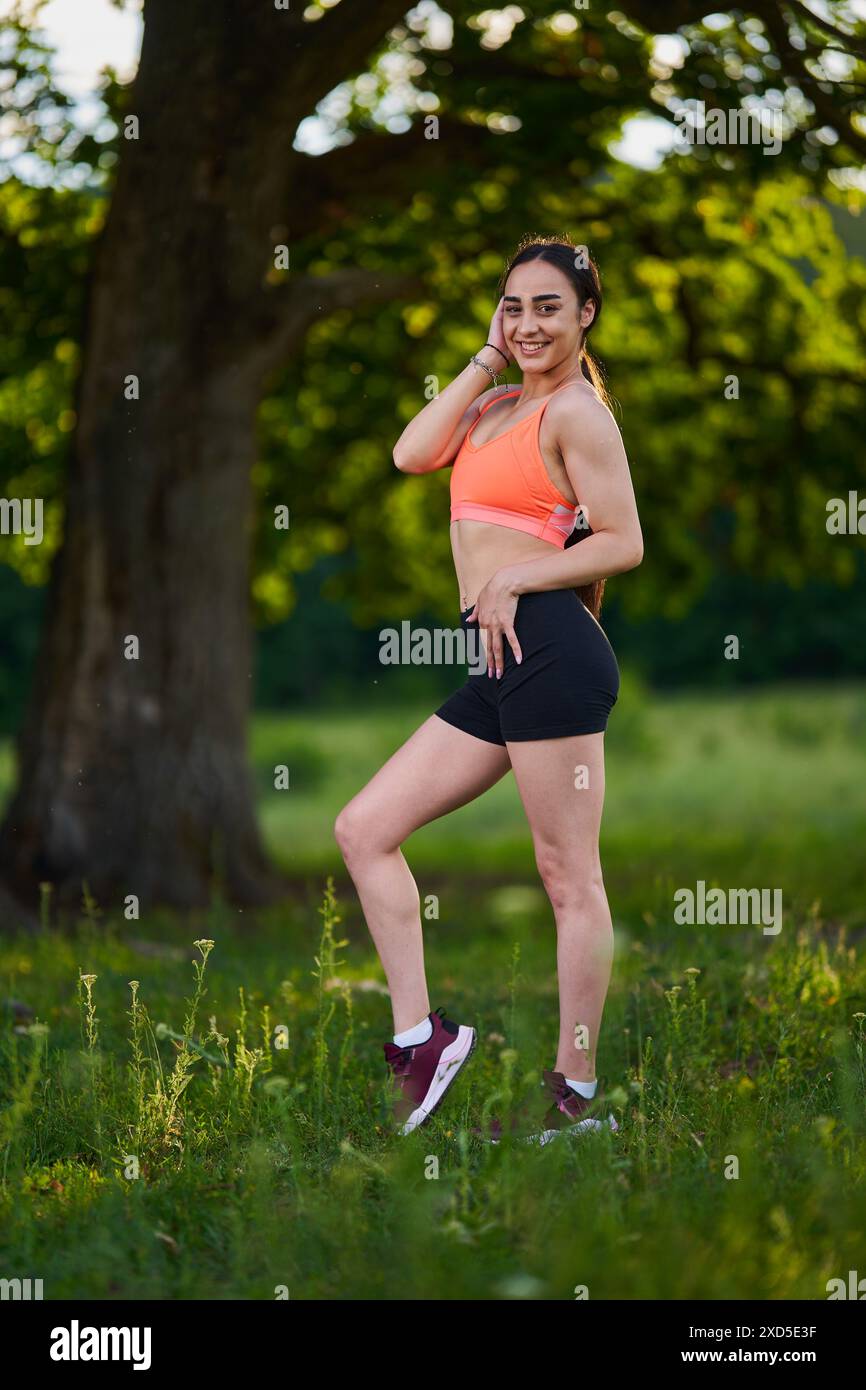 Fitness model posing in varioius postures on a meadow by the forest ...
