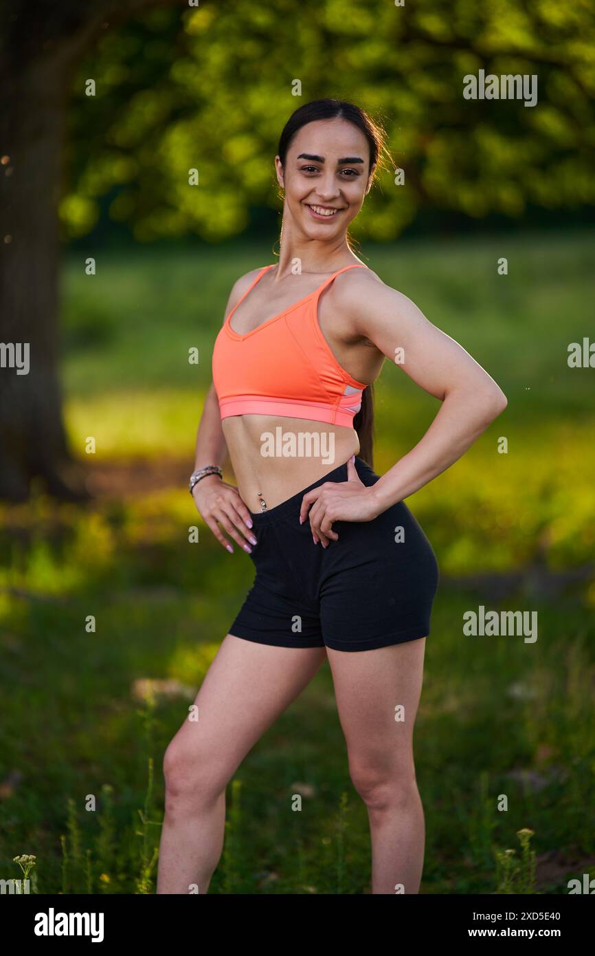 Fitness model posing in varioius postures on a meadow by the forest ...
